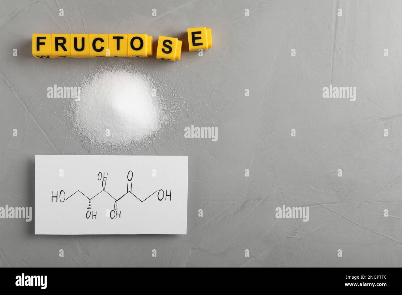 Word Fructose made of yellow cubes, sugar and paper with scheme on grey ...