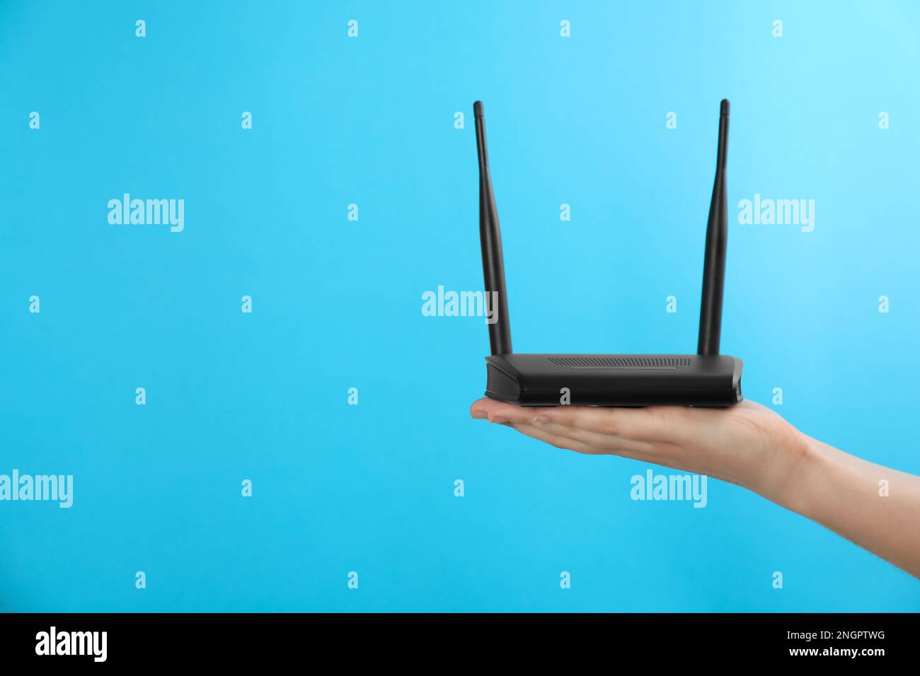 Woman holding modern Wi-Fi router on light blue background, closeup ...