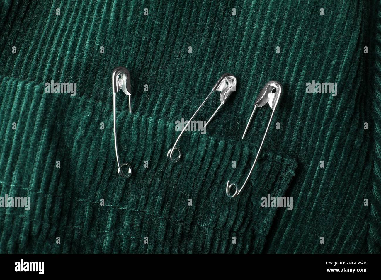 Metal safety pins on green fabric, closeup Stock Photo - Alamy