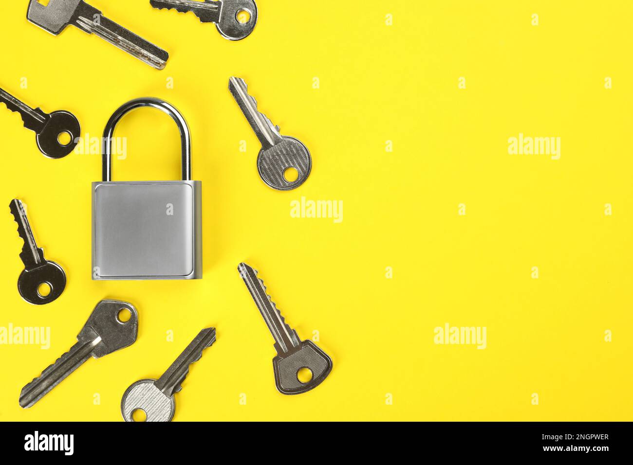 Modern padlock with keys on yellow background, flat lay. Space for text ...