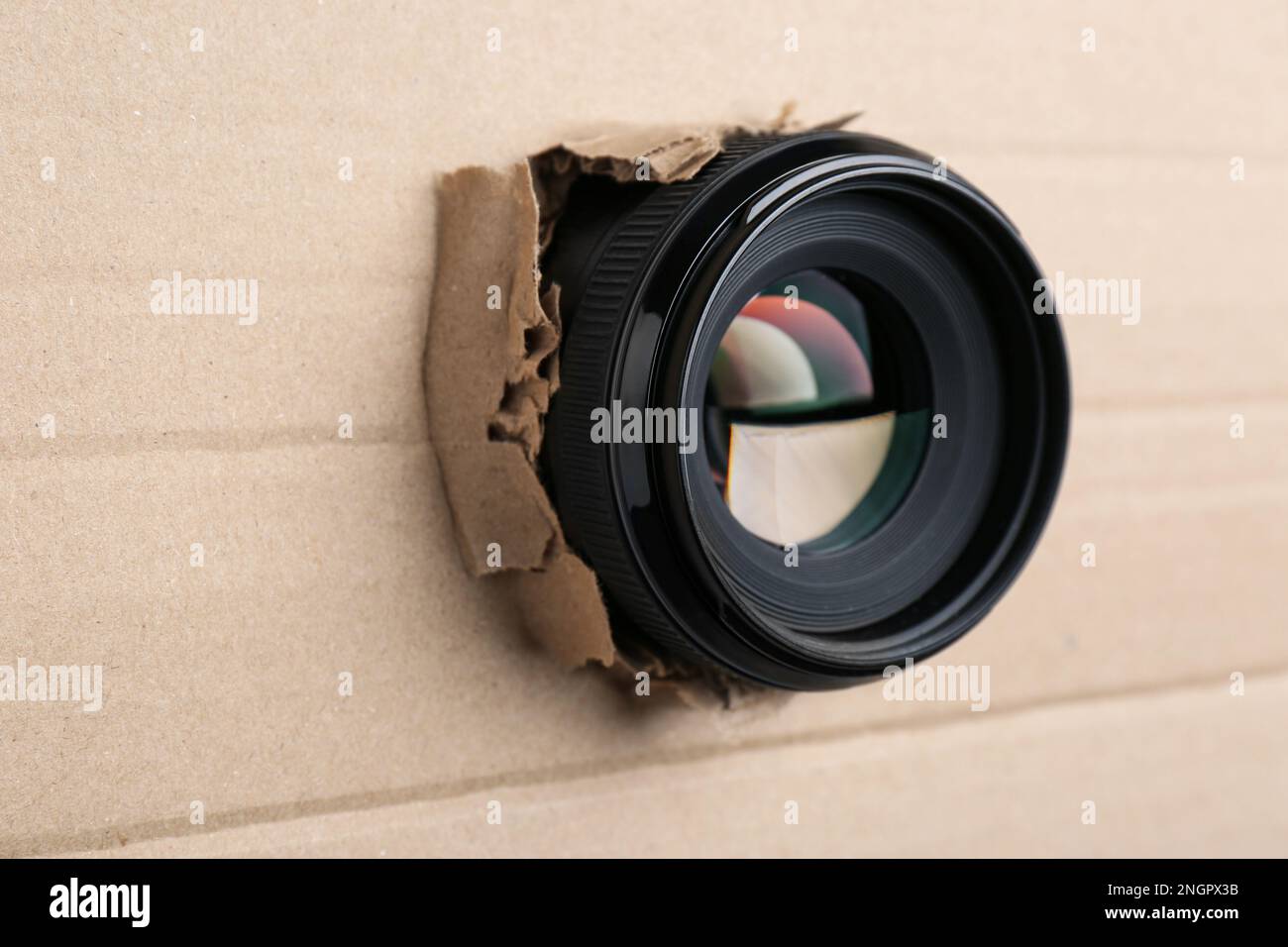 Hidden camera lens through hole in cardboard, closeup Stock Photo - Alamy