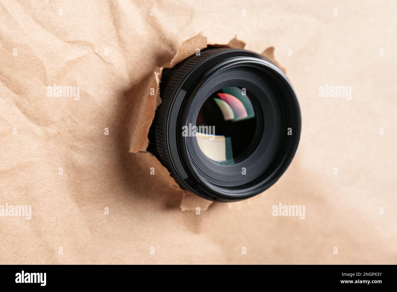 Hidden camera lens through hole in paper, closeup Stock Photo - Alamy