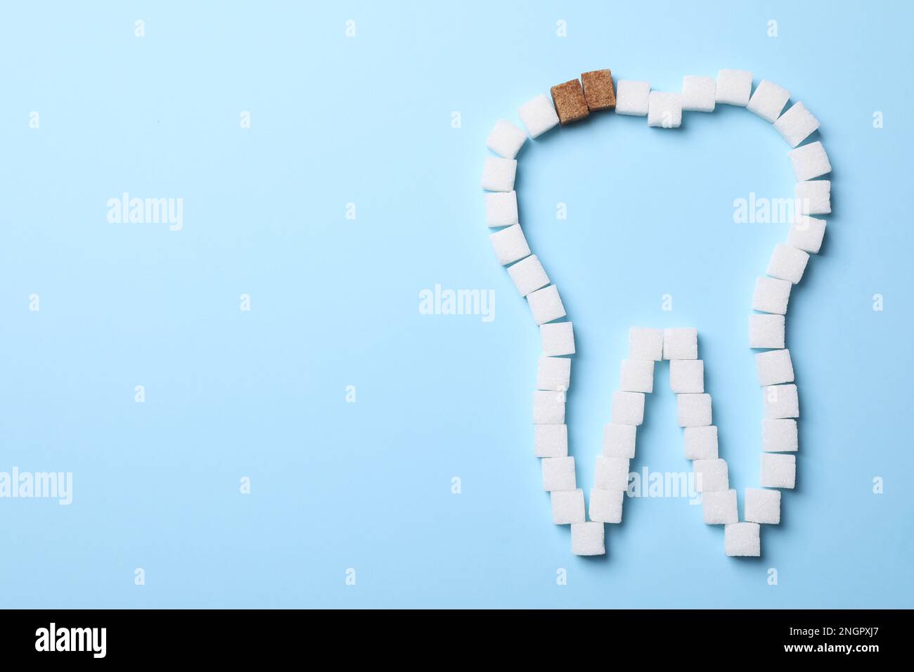 Two brown sugar cubes among white ones in tooth outline symbolizing ...