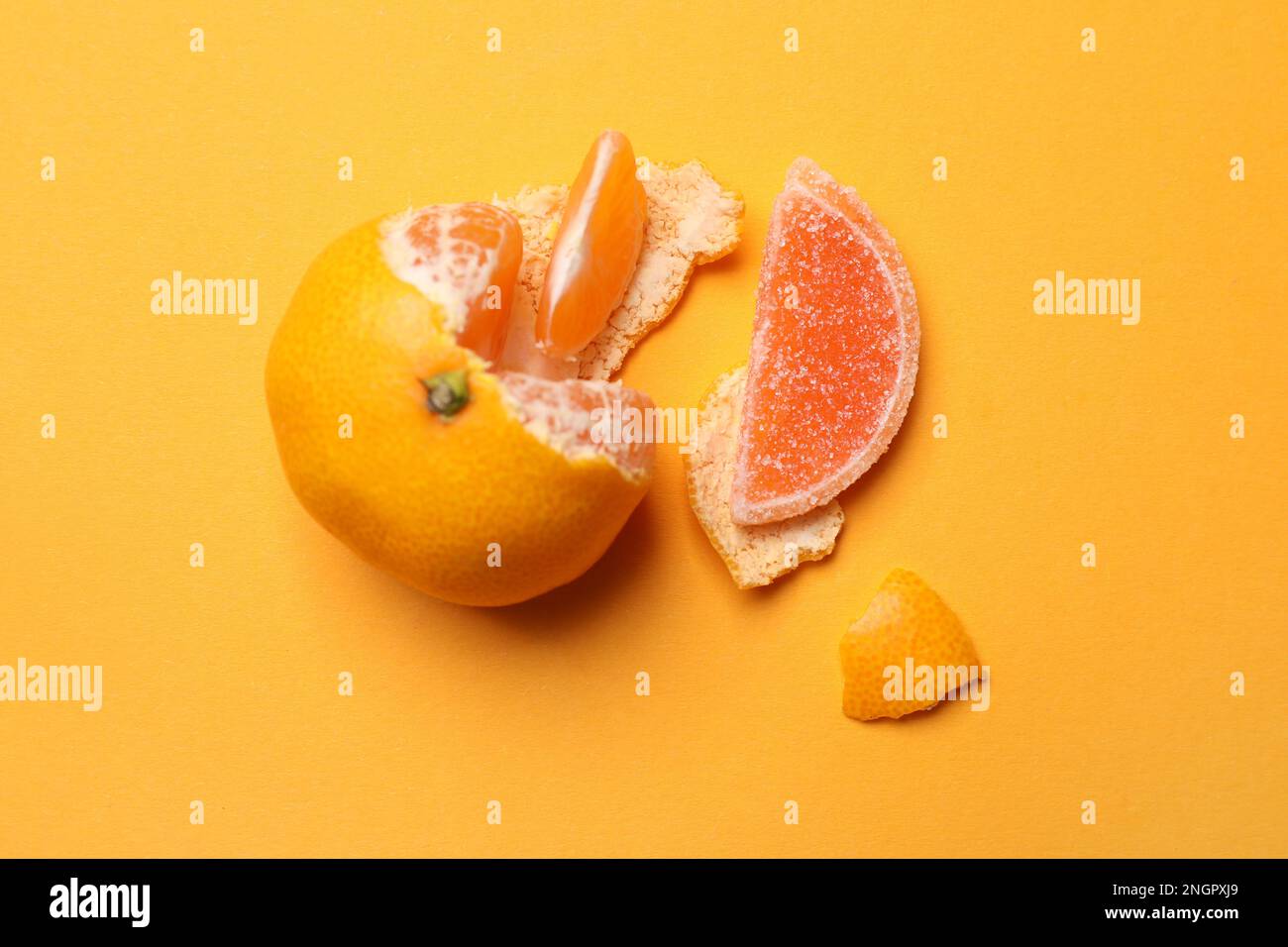 Fresh tangerine with one jelly candy as its segment on orange ...