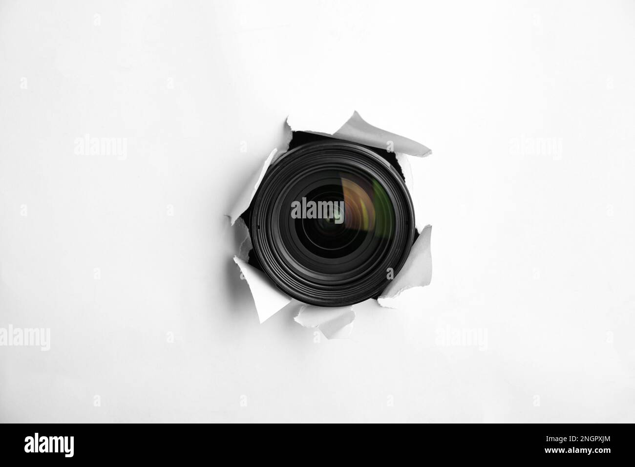 Hidden camera lens through torn hole in white paper Stock Photo - Alamy