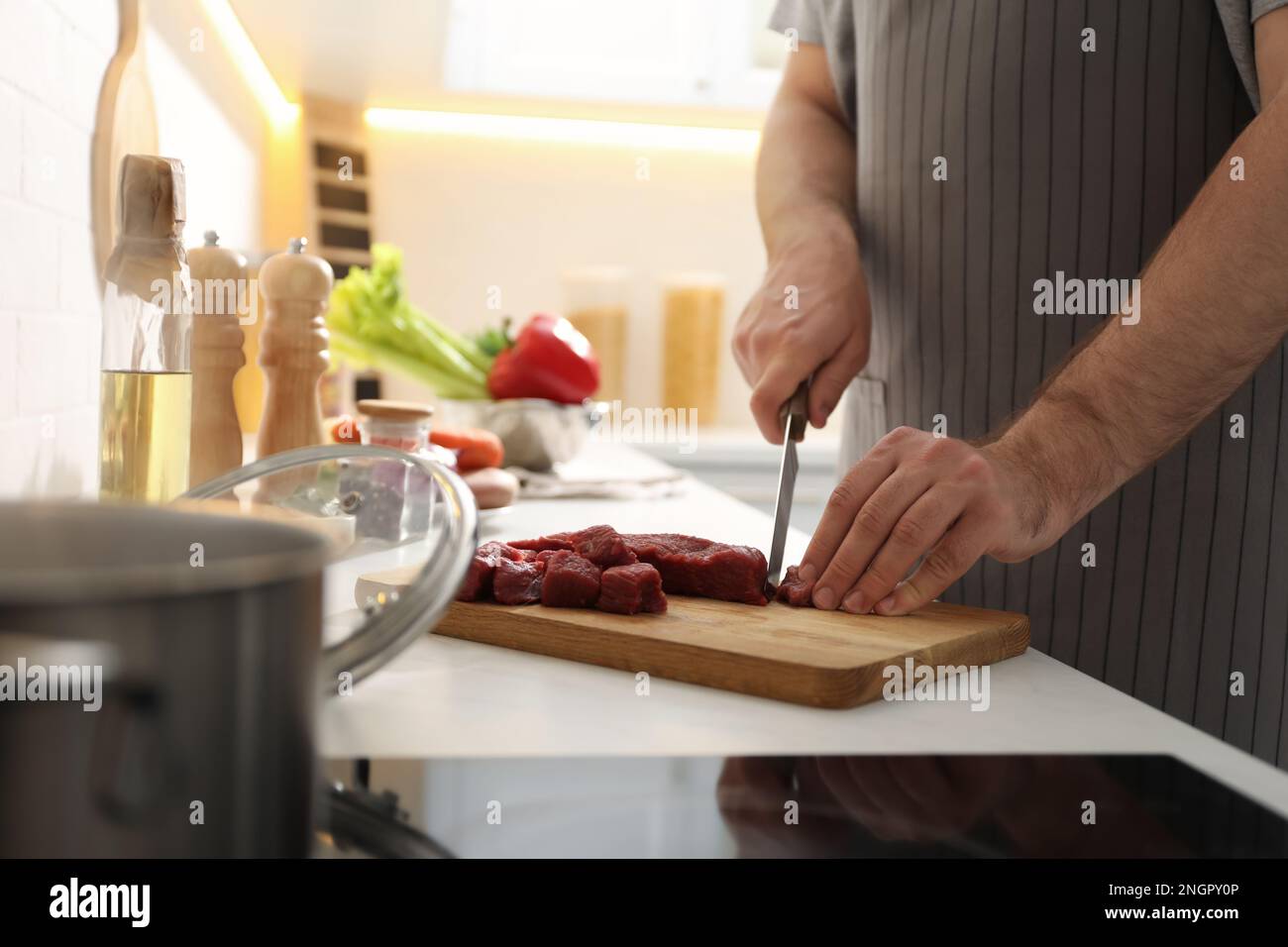 Man cutting meat to make bouillon in kitchen, closeup. Homemade recipe ...