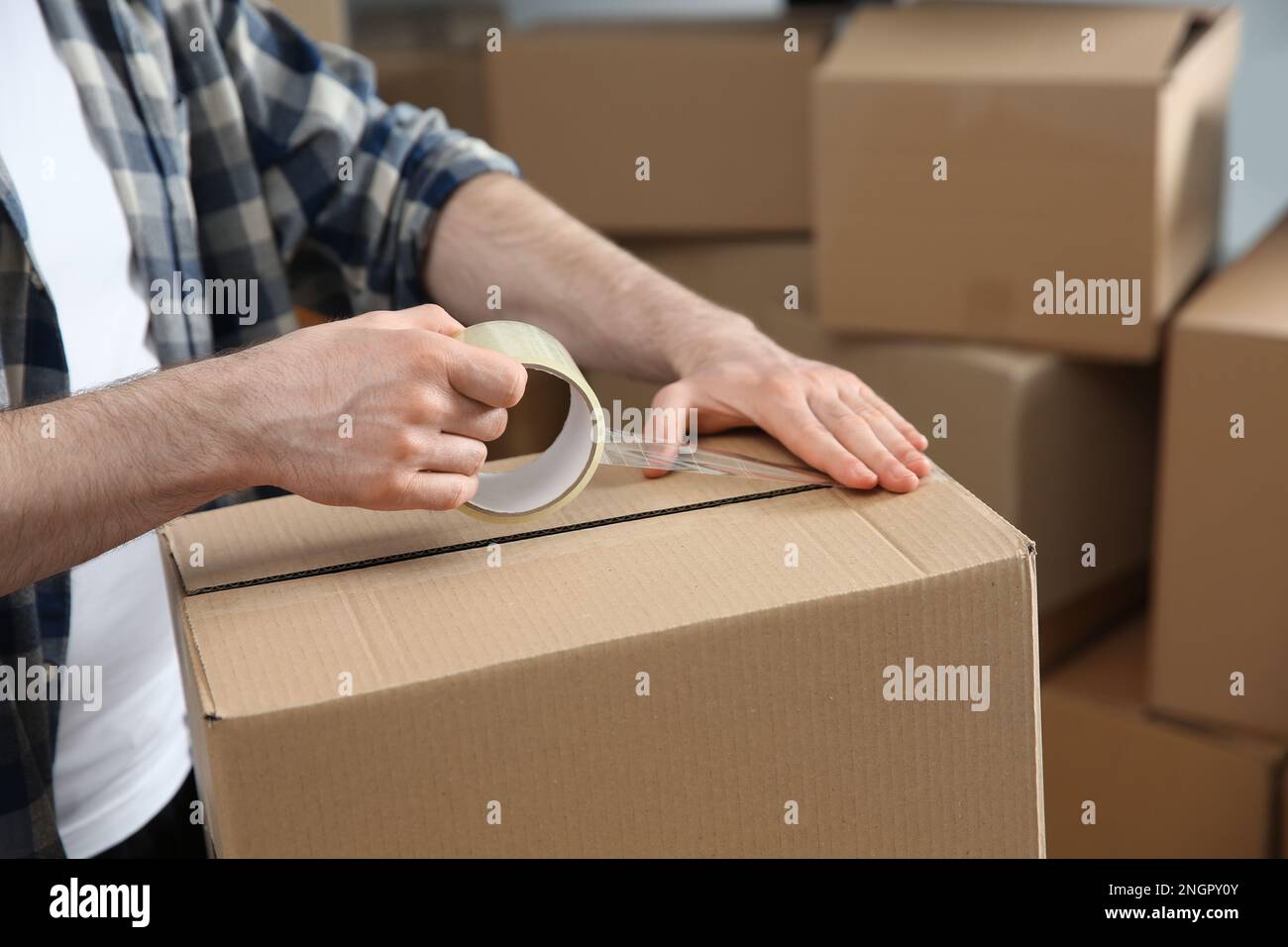 Man taping cardboard box indoors, closeup. Moving day Stock Photo - Alamy