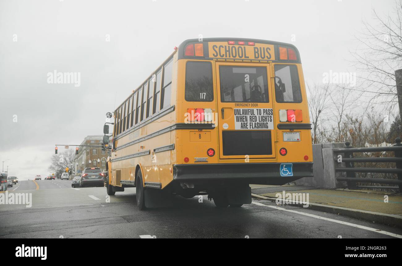 yellow school bus in public with stop sign showing Stock Photo - Alamy