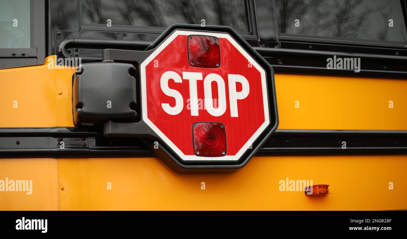 yellow school bus in public with stop sign showing Stock Photo - Alamy