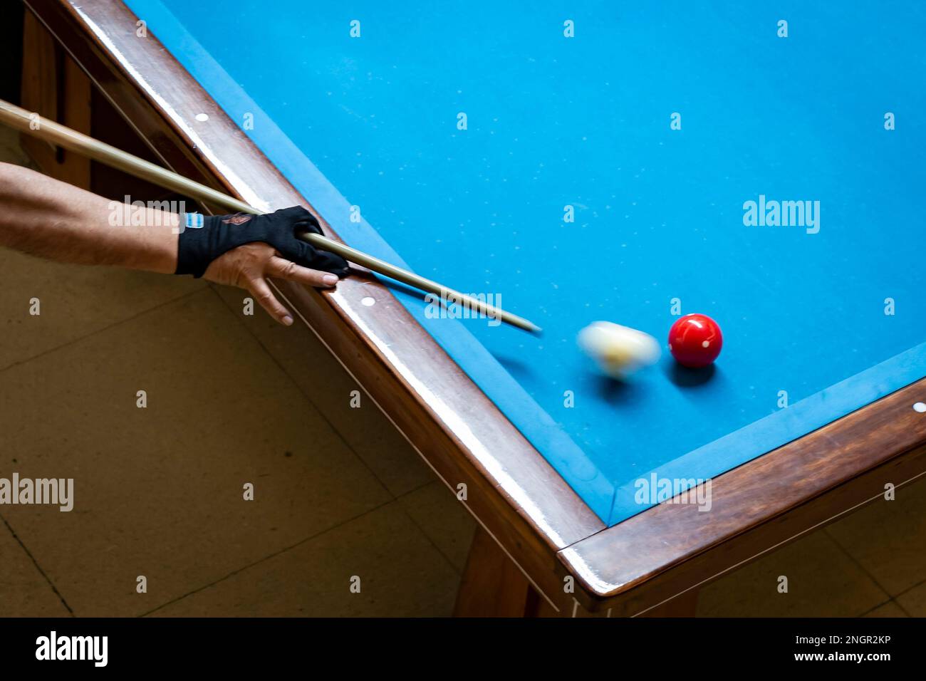 Player's arm holding cue above pool table. The player has just struck ...