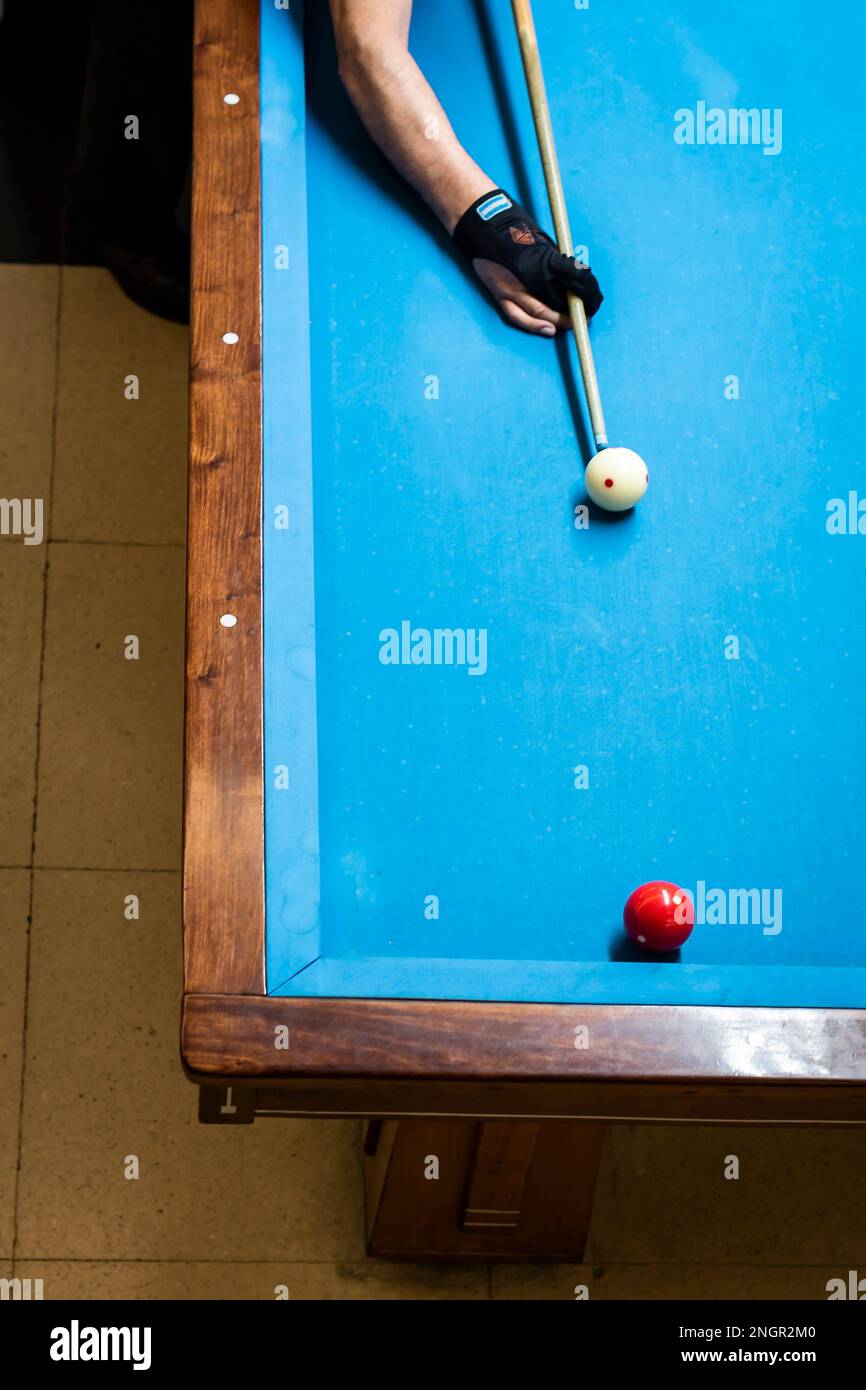 Player's arm holding cue above pool table. The player is about to ...