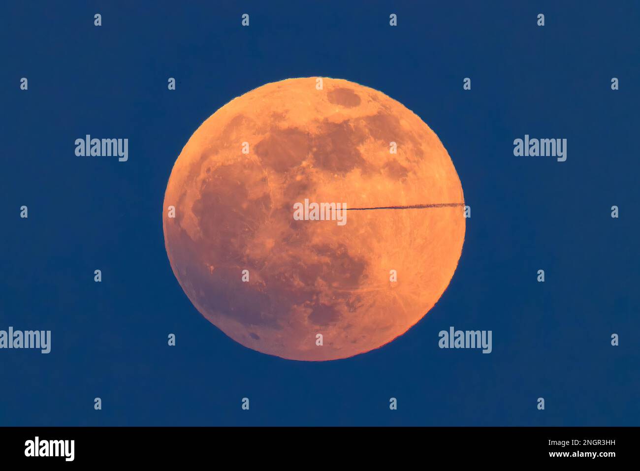 A jet and its contrail crosses the full moon on the night of the blood ...