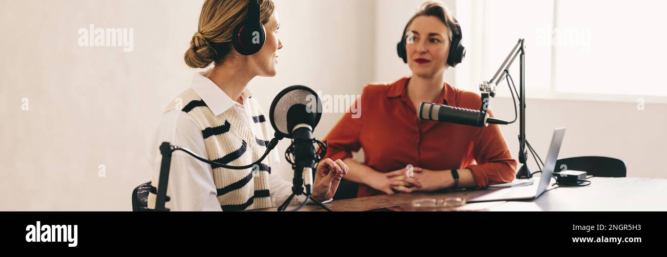 Female radio host interviewing a guest on her show in her home studio ...