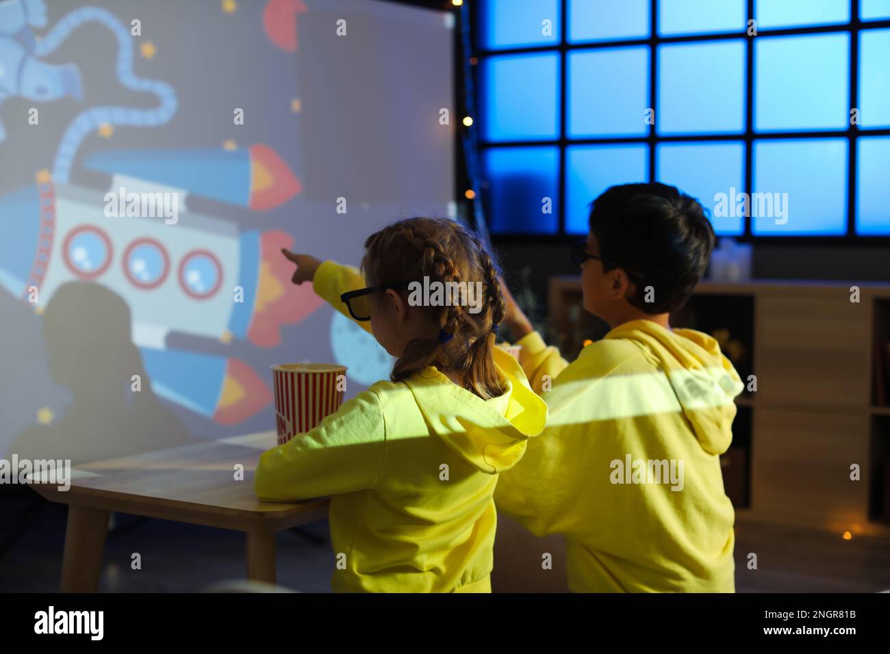 Little children in 3D glasses with popcorn watching cartoons on ...