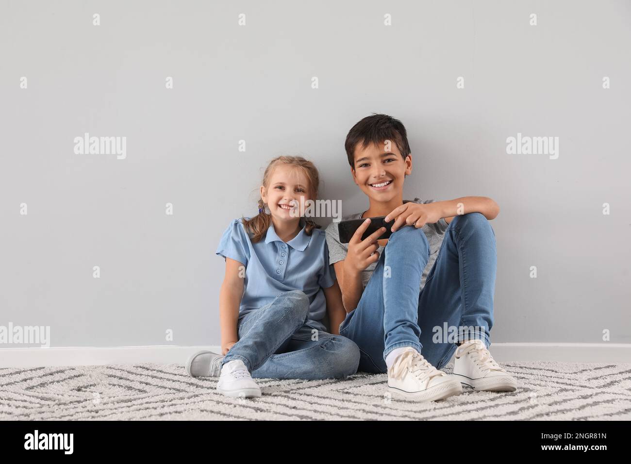 Little boy and his sister watching cartoons on TV near light wall Stock ...
