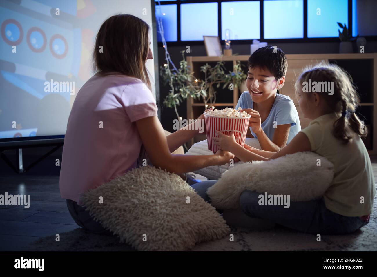Mother with her little children and popcorn watching cartoons on ...