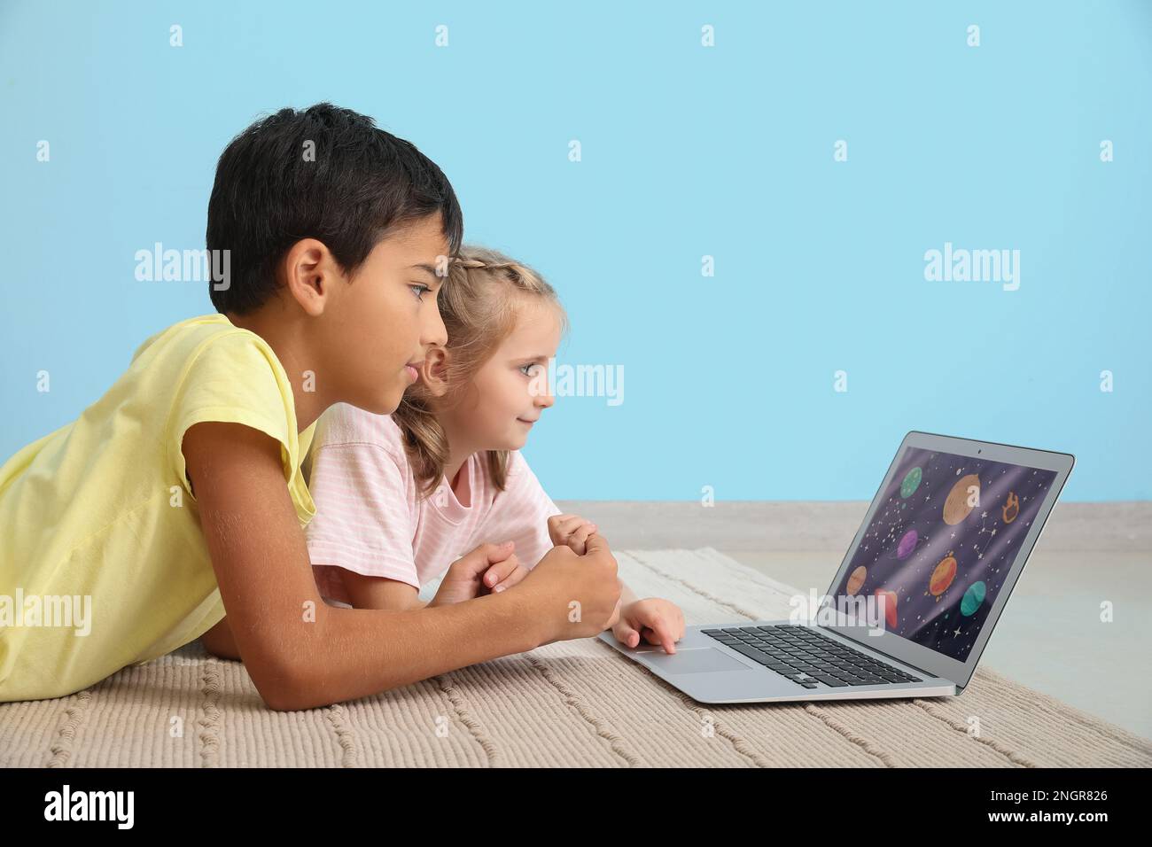Little boy and girl watching cartoons on laptop near blue wall Stock ...
