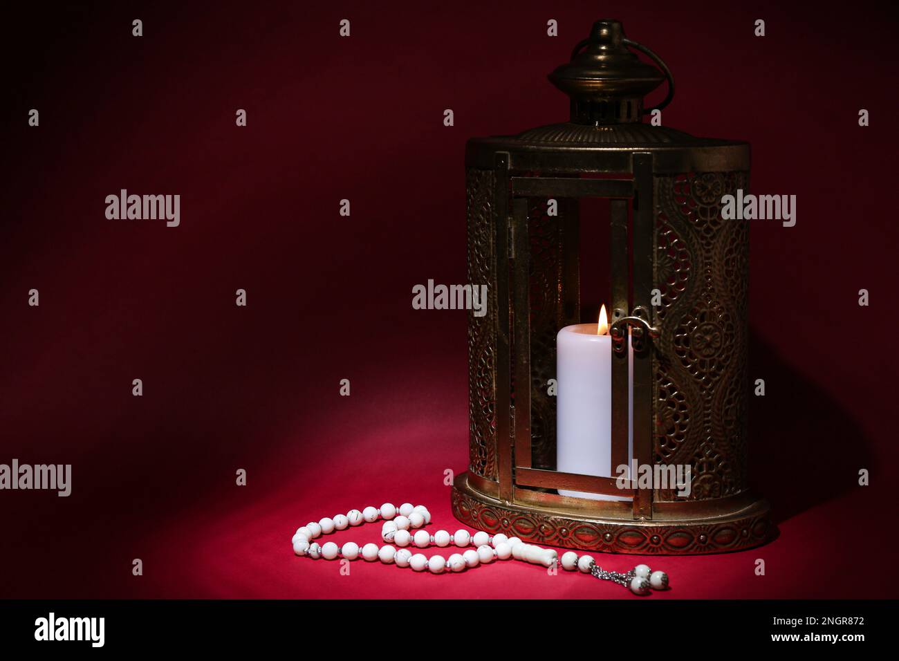 Muslim lantern with burning candle and tasbih for Ramadan on dark color ...