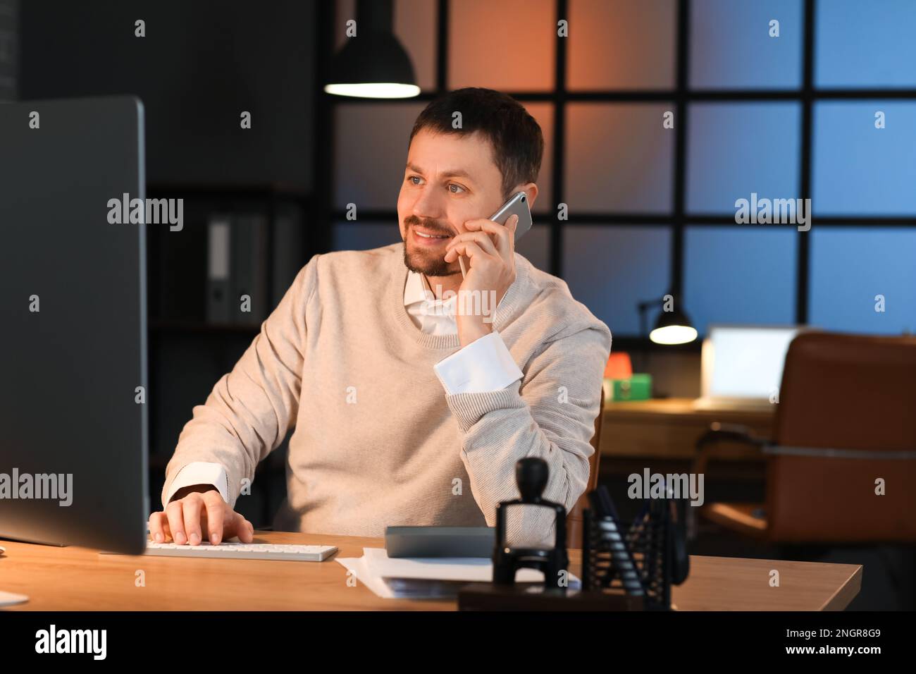 Male accountant talking by mobile phone in office at night Stock Photo ...