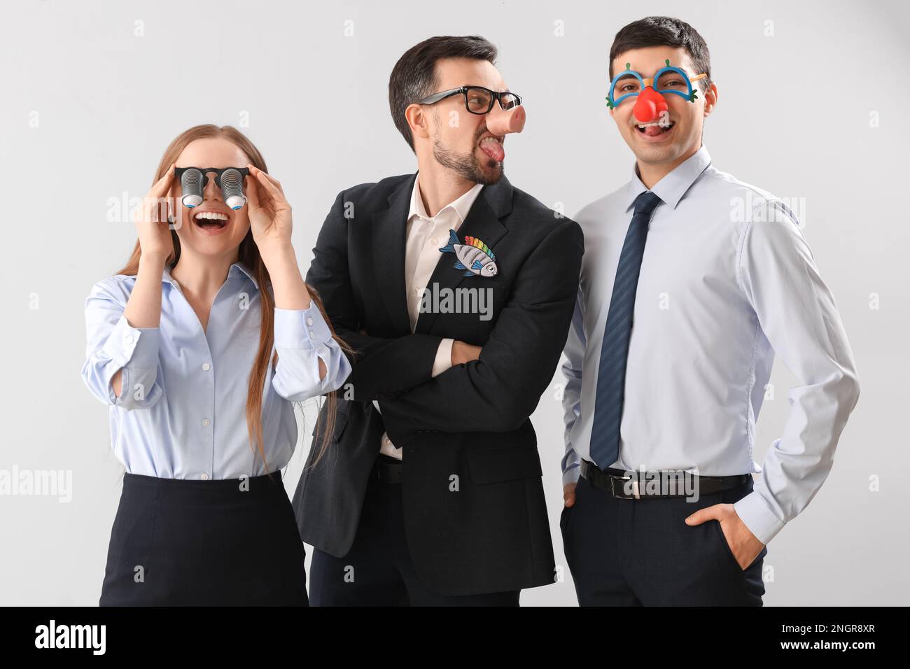 Business colleagues in funny disguise on light background. April Fools ...