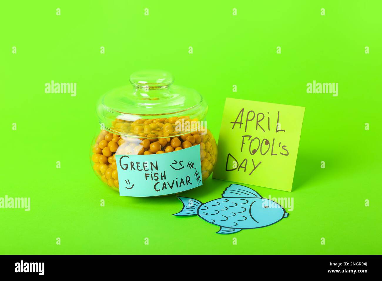 Glass jar of green peas and sticky note with text FOOL'S DAY on color ...