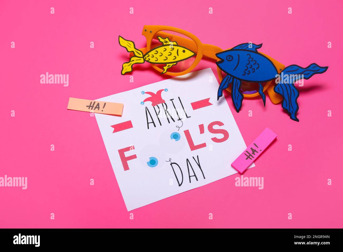 Card with text APRIL FOOL'S DAY, eyeglasses and paper fishes on pink ...
