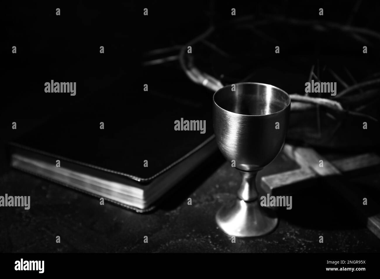 Wine cup, crown of thorns, cross and Holy Bible on dark background ...