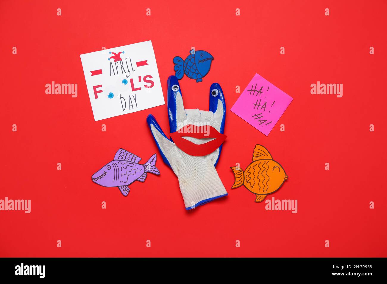 Creative composition with glove, card and paper fishes on red ...