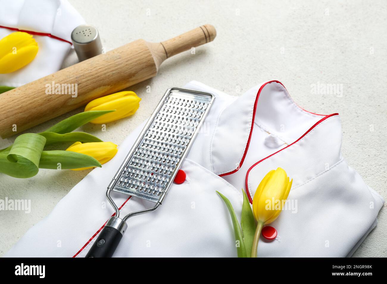Chef's uniform with utensils and tulips on white background, closeup ...