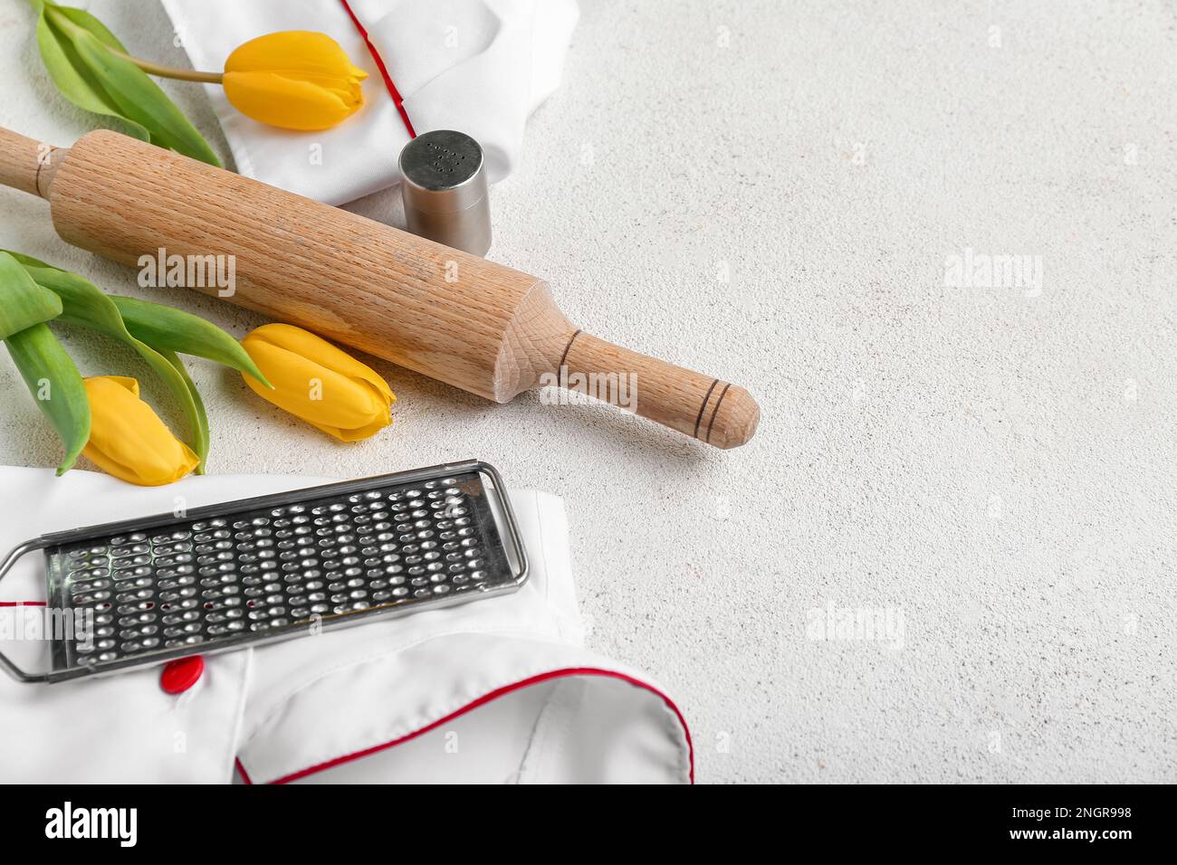 Chef's uniform with utensils and tulips on white background, closeup ...