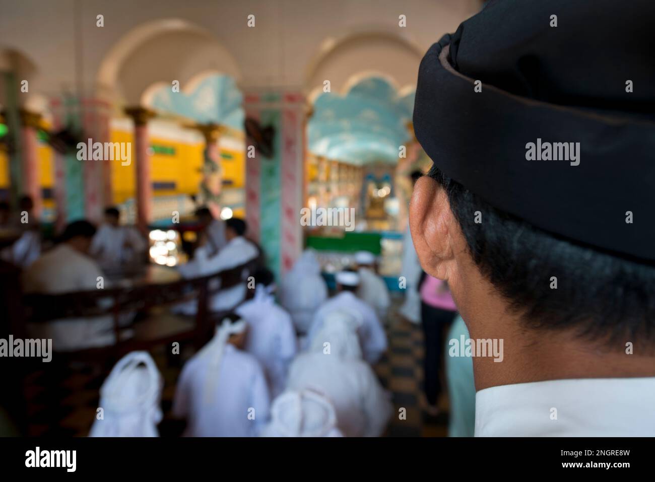 View from behind nake Caodaist disciple with hat near musicians playing ...