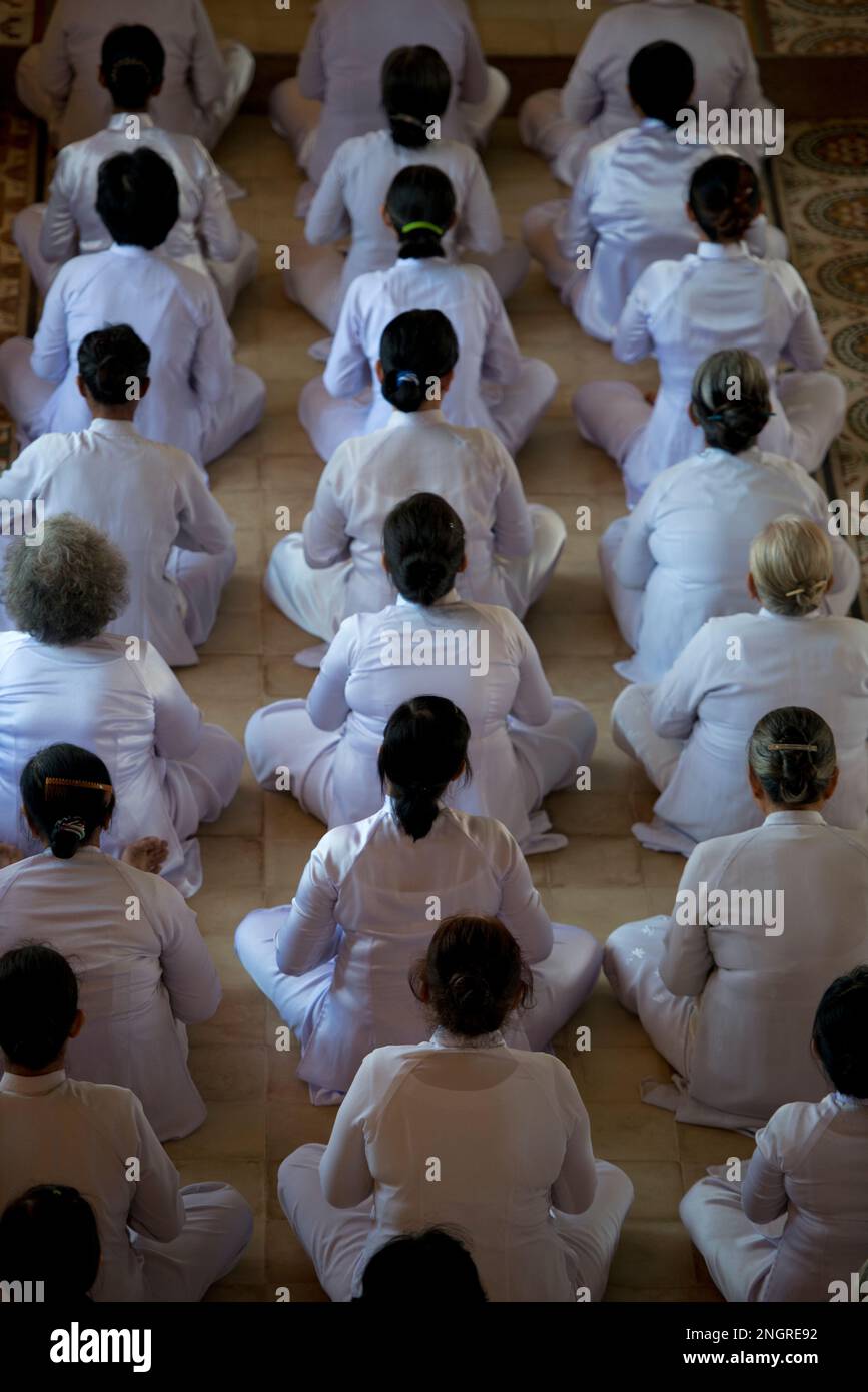 Female Caodaist disciples sitting during ceremony, Cao Dai Temple, Tay ...