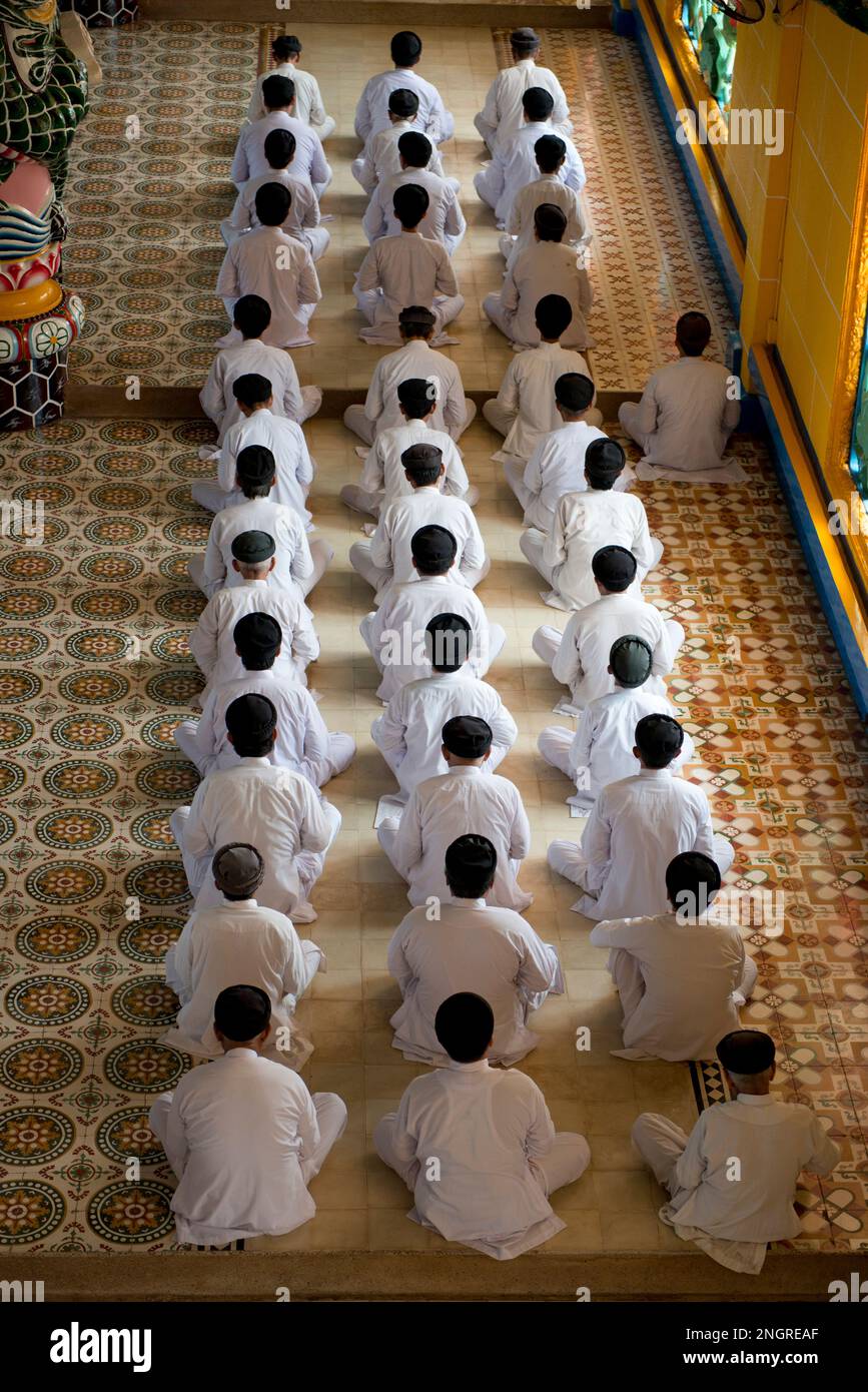 Male Caodaist disciples sitting during ceremony, Cao Dai Temple, Tay ...