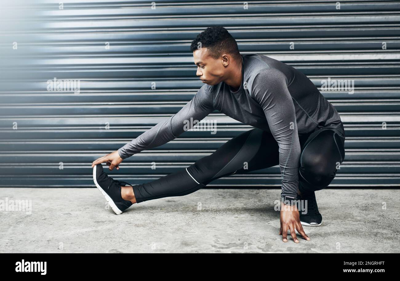 Keep those muscles warm and wide awake. a sporty young man stretching ...