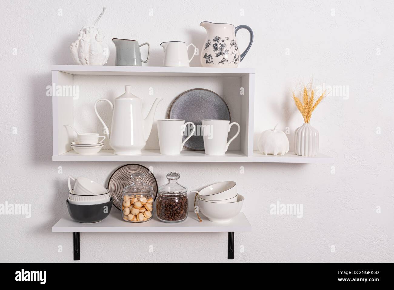 beautiful white shelves with kitchen utensils on a white textured wall ...
