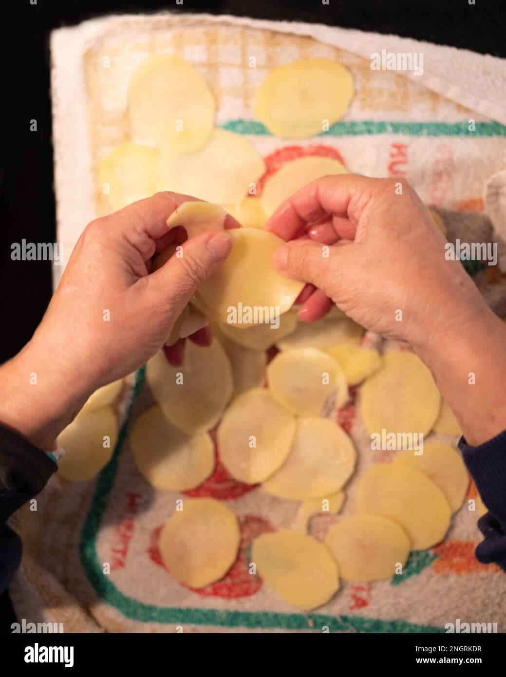 mature woman housewife selecting and drying potato slices for cooking ...