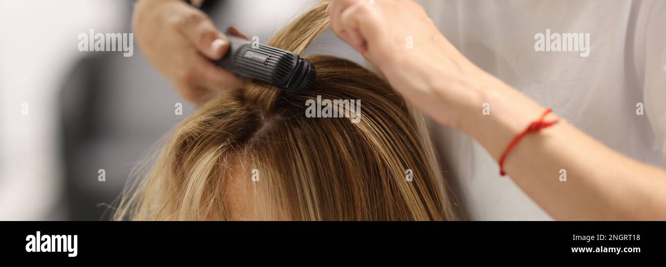 Pulling strands of hair with professional iron care Stock Photo - Alamy