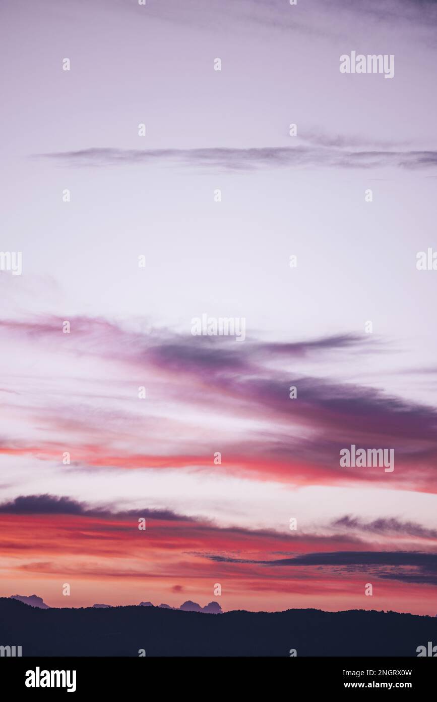 A mesmerizing view of the sky, with soft pink, violet, and purple puffy clouds stretching ...