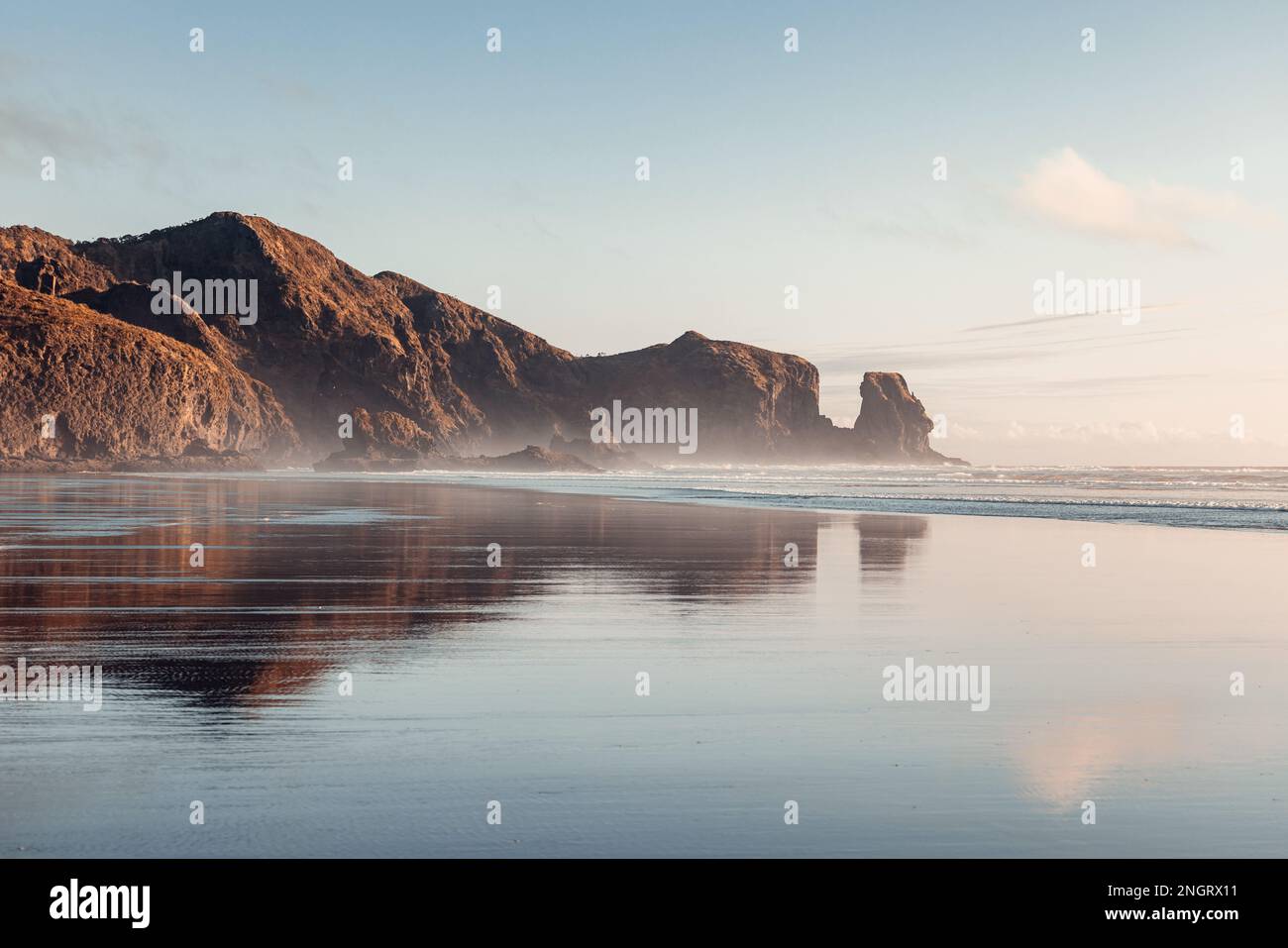 Piha beach captured at sunset, with the warm colors of the sky ...