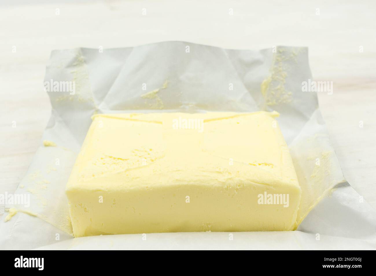 Fresh piece of butter on the packaging paper closeup, whole piece Stock ...