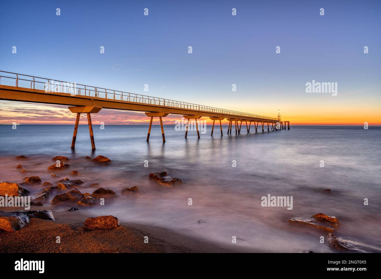 The sea pier of Badalona, known as Pont del Petroli, before sunrise ...