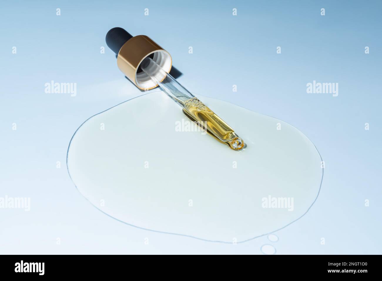 close up of pipette with pouring liquid serum and shadows on blue ...