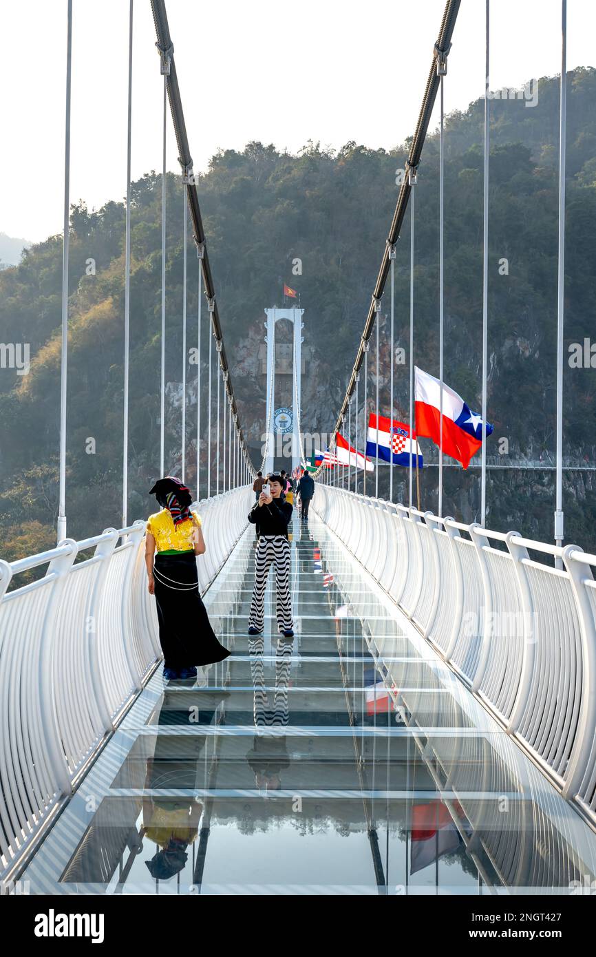 A female tourist enjoys walking on Bach Long Glass Bridge. This is the ...