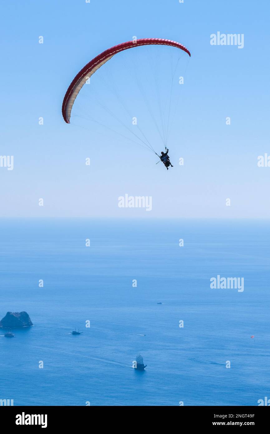 Paragliding in the sky. Paraglider tandem flying over the sea with blue ...