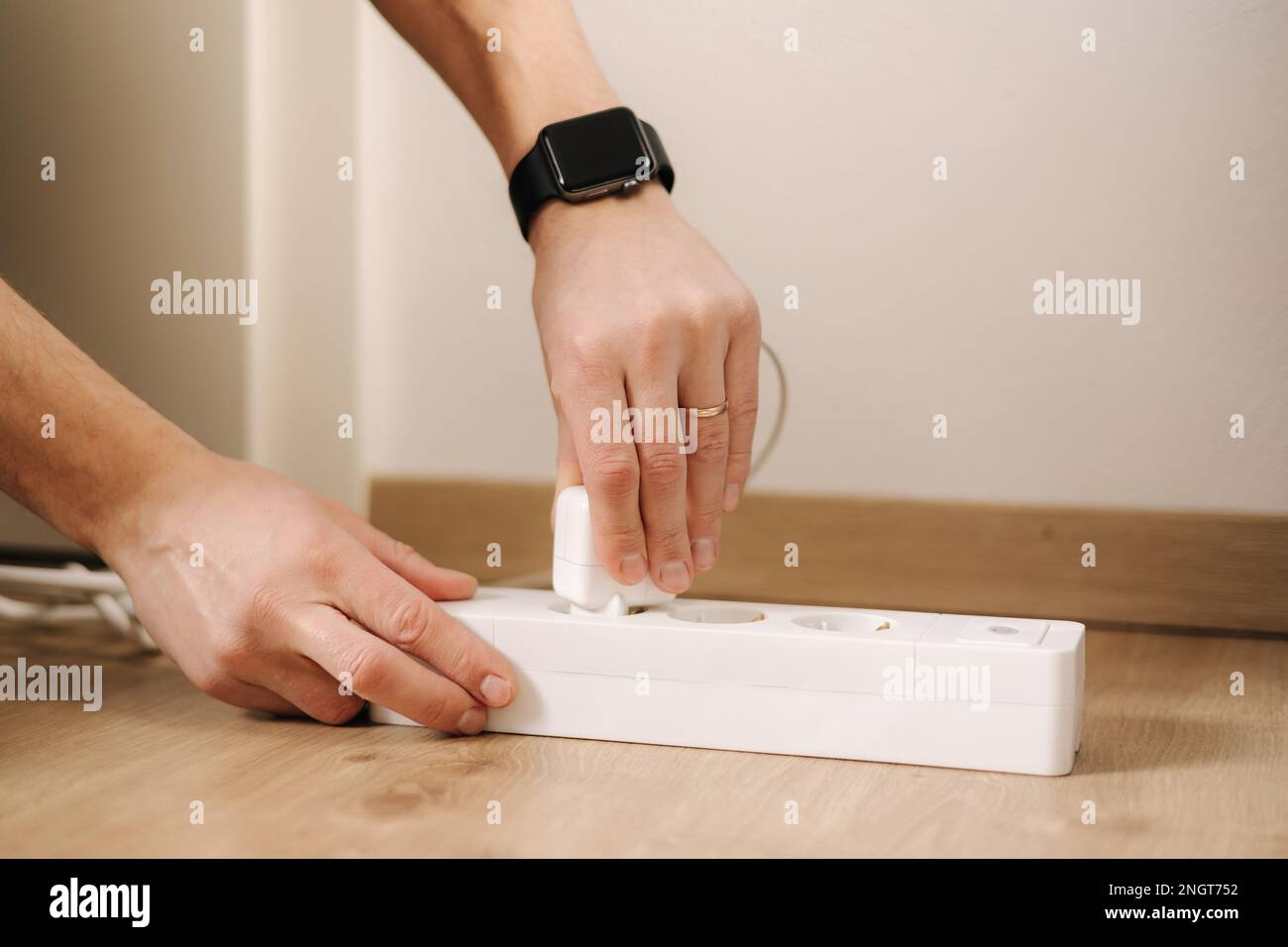 Human hand puts the charger into the extension cord. White cable ...