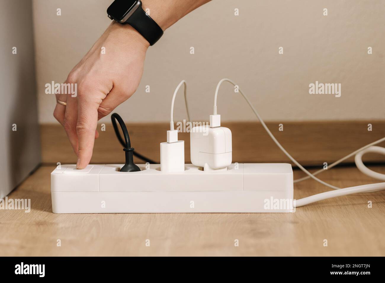 Human hand puts the charger into a filled extension cord. White cable ...