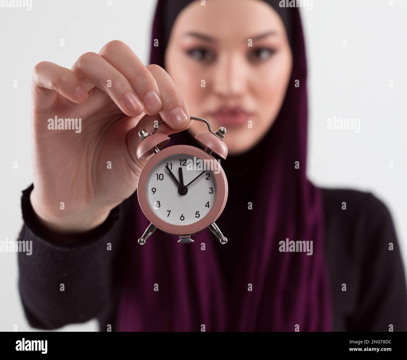Beautiful arab businesswoman wearing hijab and holding a small clock ...