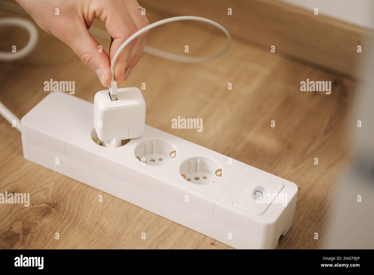 Human hand puts cable into the charger. Extension cord. White cable ...