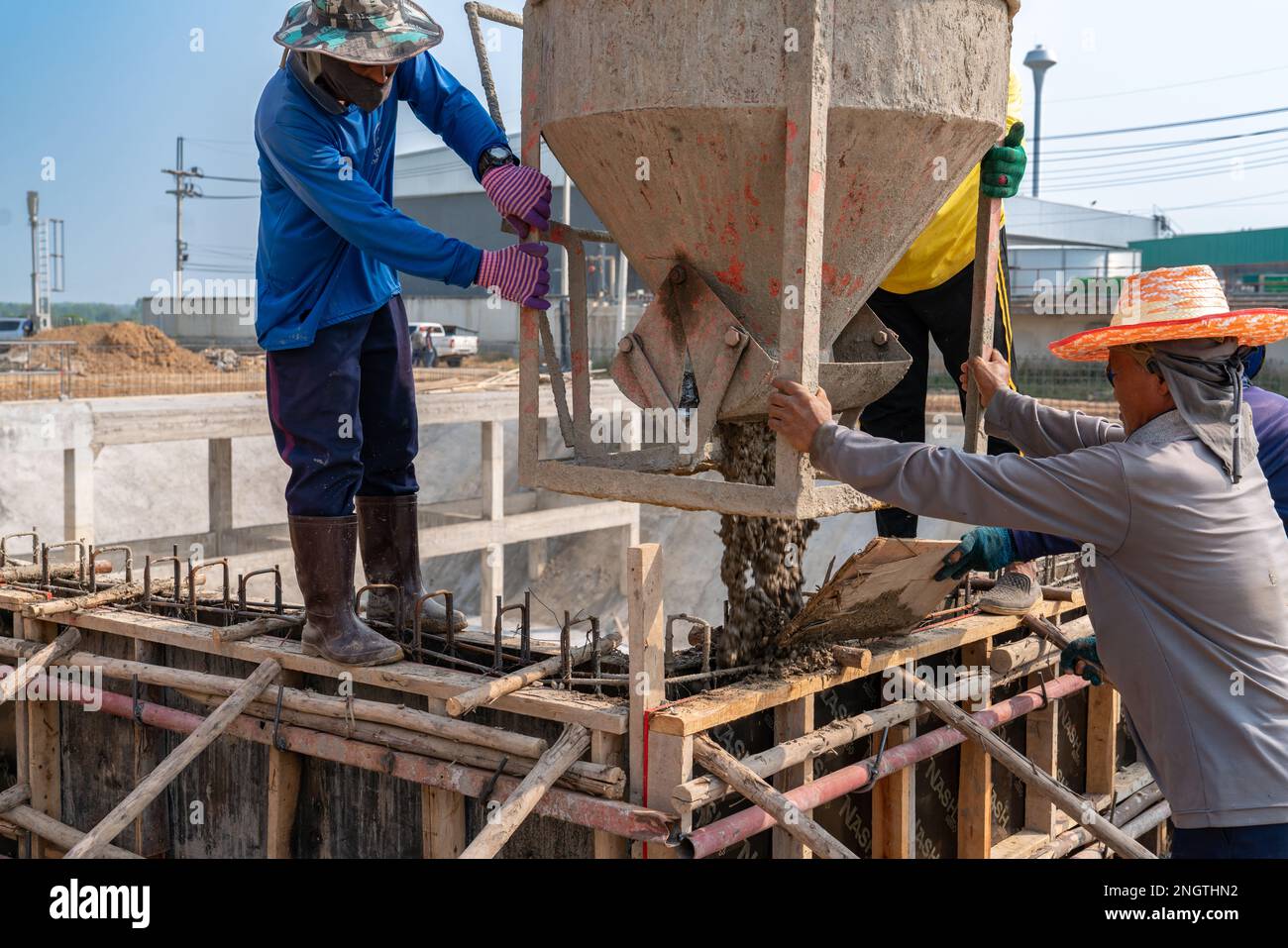 Workers pouring concrete from bucket into formwork at construction site ... Workers pouring concrete from bucket into formwork at construction site ...