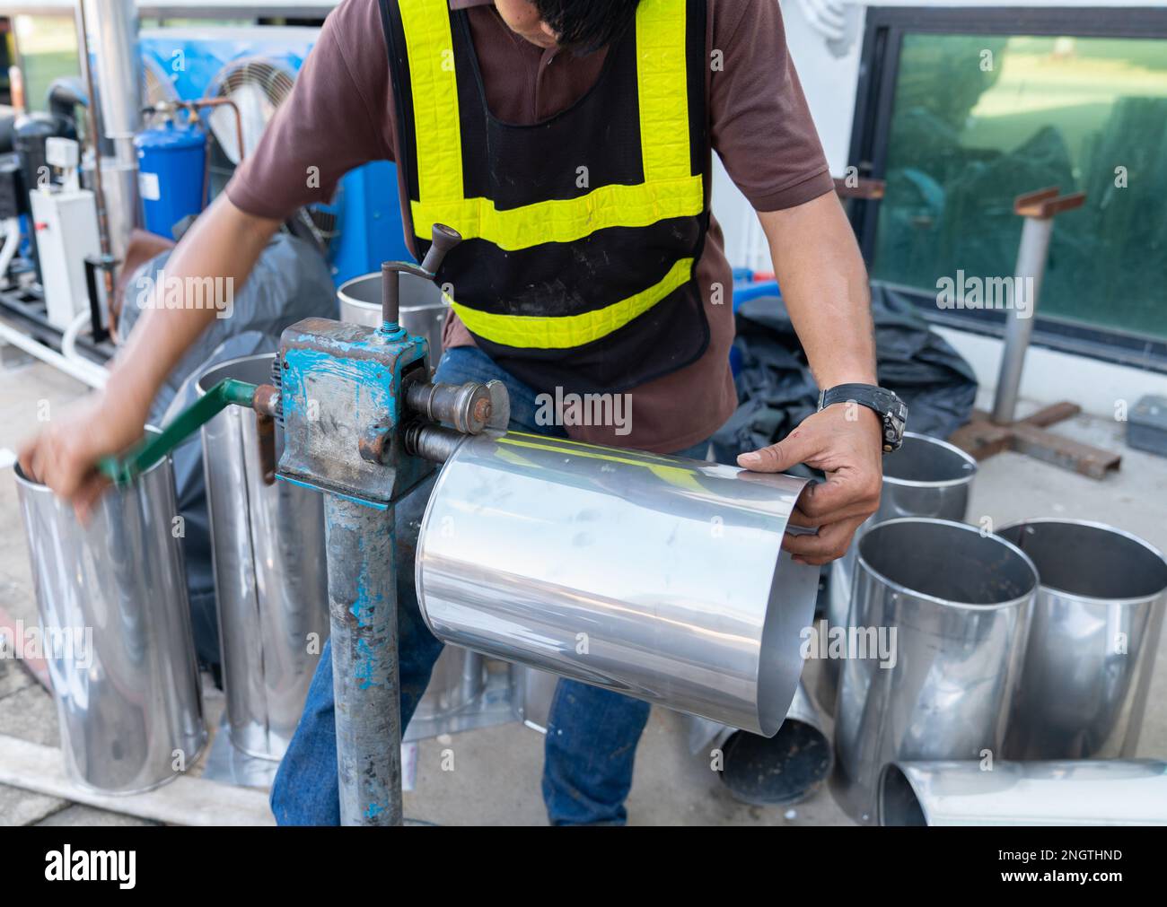 Worker turn rolled steel sheet rim on plate rolling machine in factory ...